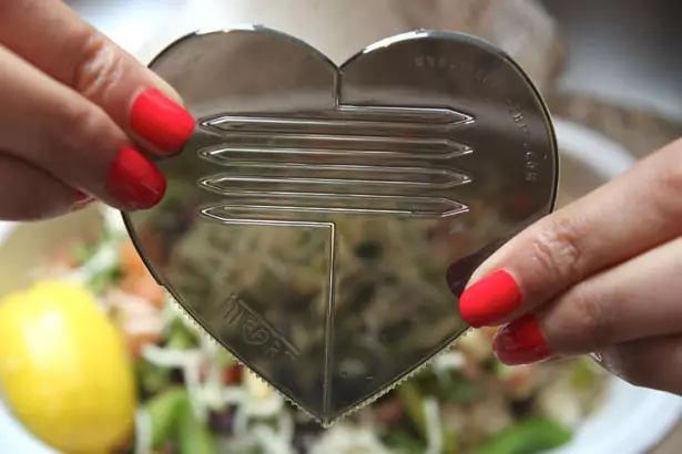 La part del cor biodegradable: un estri en forma de cor que s'obre per revelar dues forquilles, dos ganivets i dues culleres.