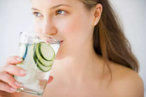 Krásne dievča pije uhorkovú vodu