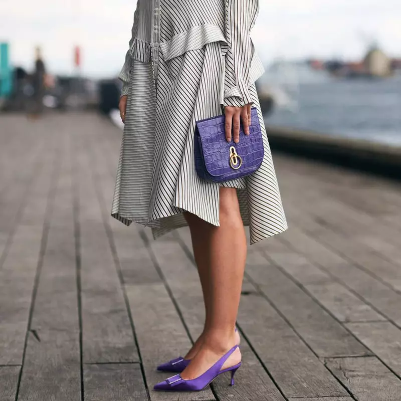 kvinde iført en kjole med lilla kattehæl-slingbacks og en lilla taske
