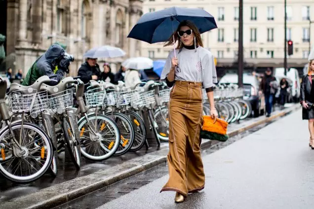 Ulični stil: žena koja nosi kišobran i nosi elegantnu odjeću za kišni dan