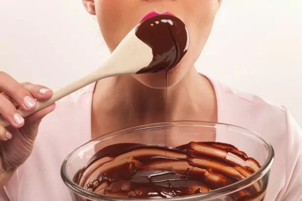Mulher lambendo chocolate de uma tigela